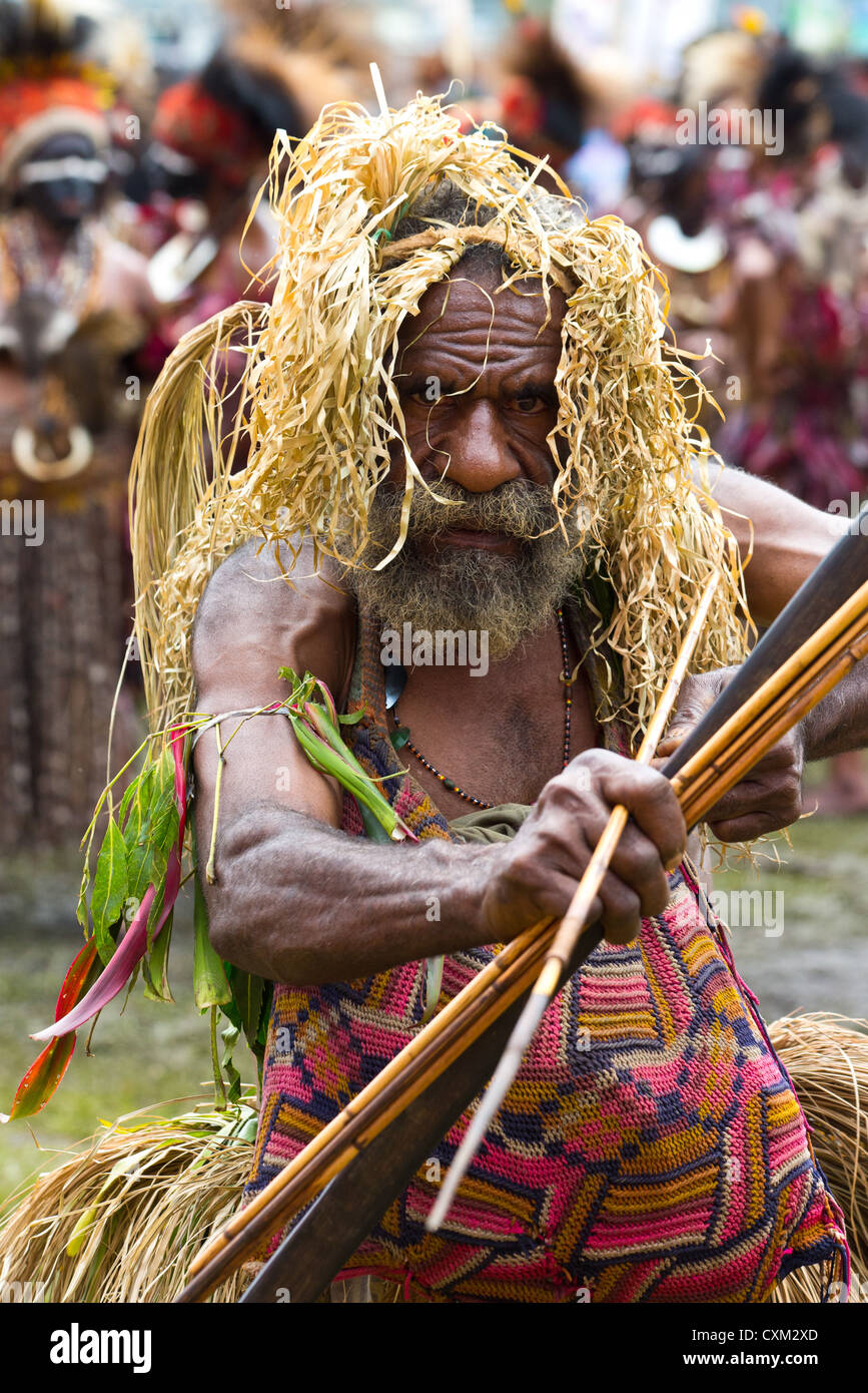 Old man wearing traditional tribal costume and pointing a bow and arrow ...