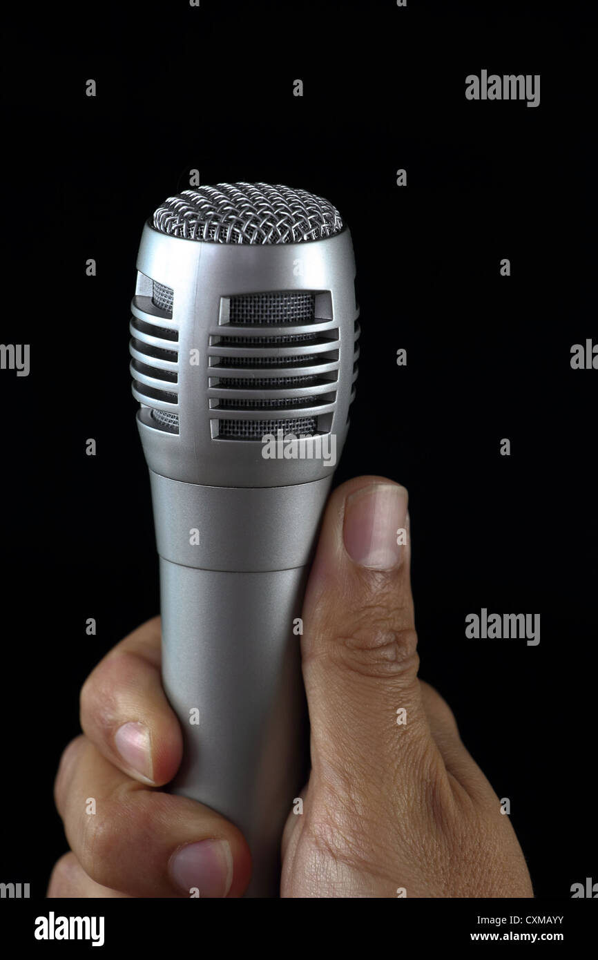 Close up of microphone in hand over black background Stock Photo - Alamy