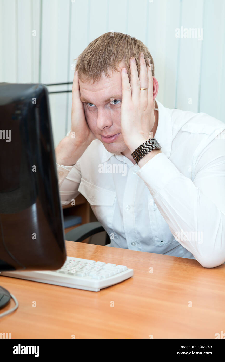 Tired young businessman working on computer at office Stock Photo - Alamy