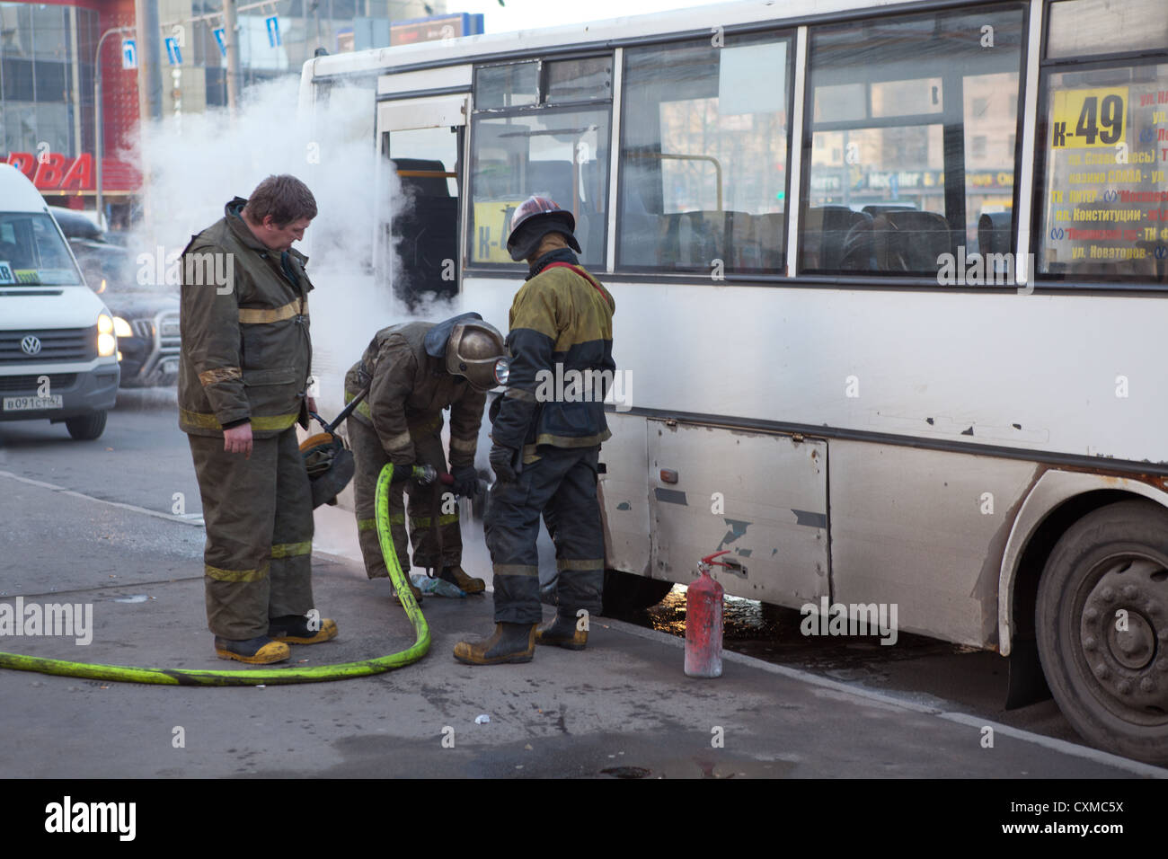 Passenger minibus in fire on city street and firefighters extinguish ...