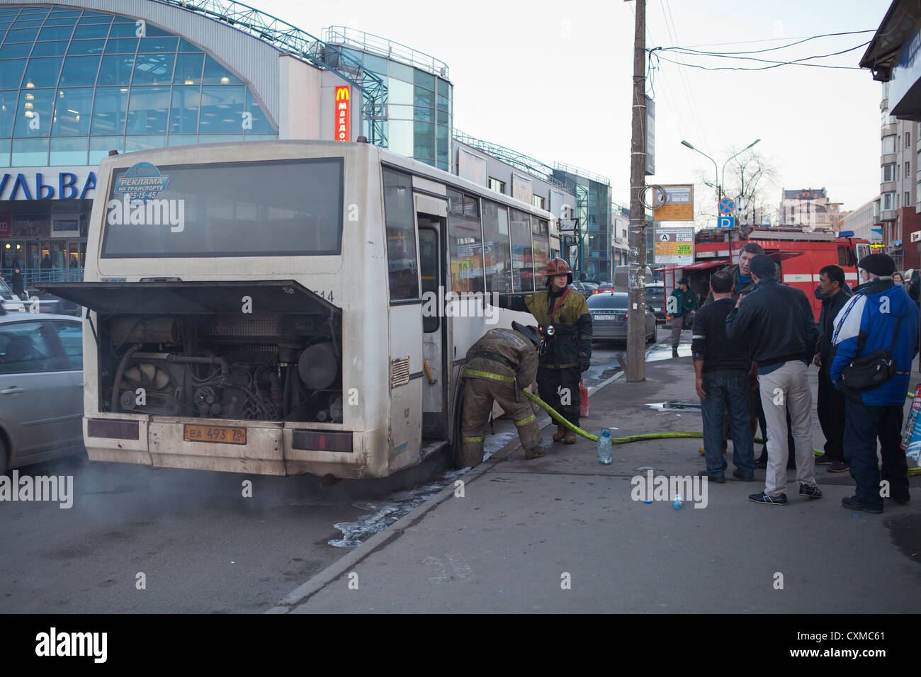 Passenger minibus in fire on city street and firefighters extinguish ...