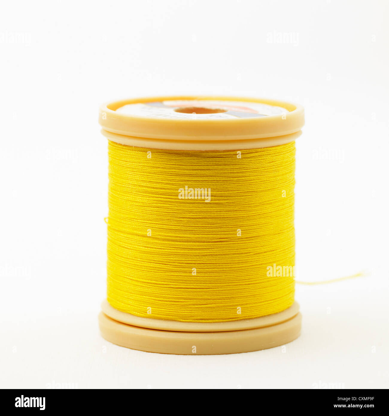 Spool of yellow sewing thread on bobbin Stock Photo - Alamy
