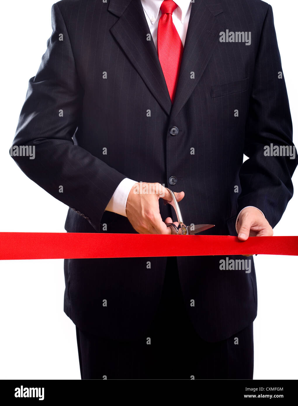 A business man wearing a blue suit cutting a red ribbon with a pair of ...