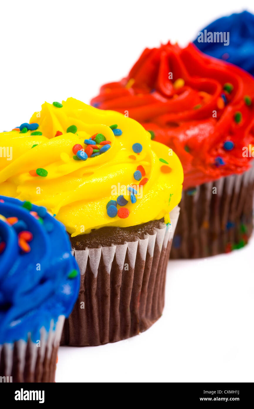 A row of bright, primary colored chocolate cupcakes on a white ...