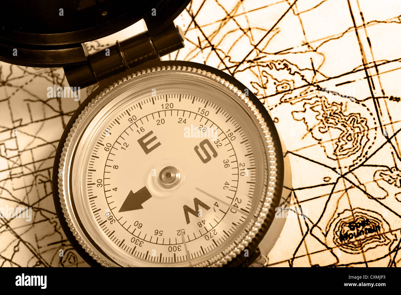 A compass lying on top of a topographical map- brown duotone or sepia ...