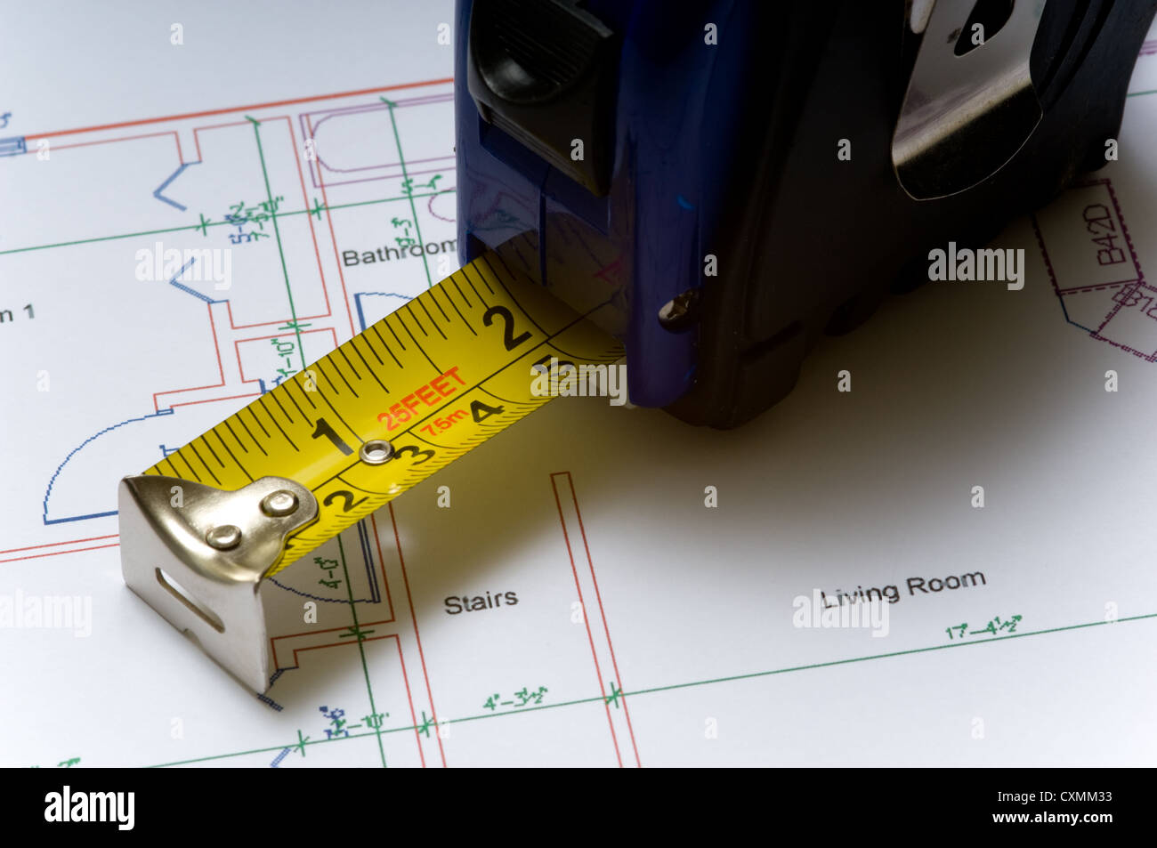 A tape measure slightly open lying on top of a house floor plan ...
