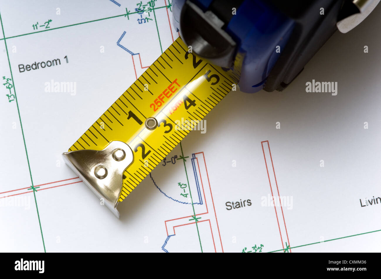 A tape measure slightly open lying on top of a house floor plan ...