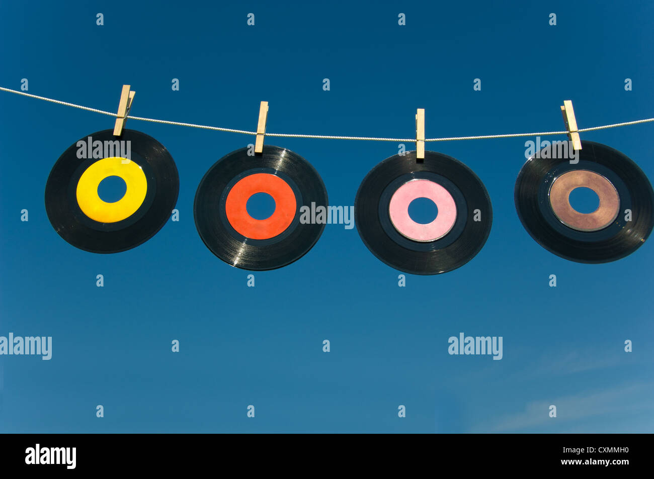 45 rpm records handing from a clothesline against a bright blue sky ...