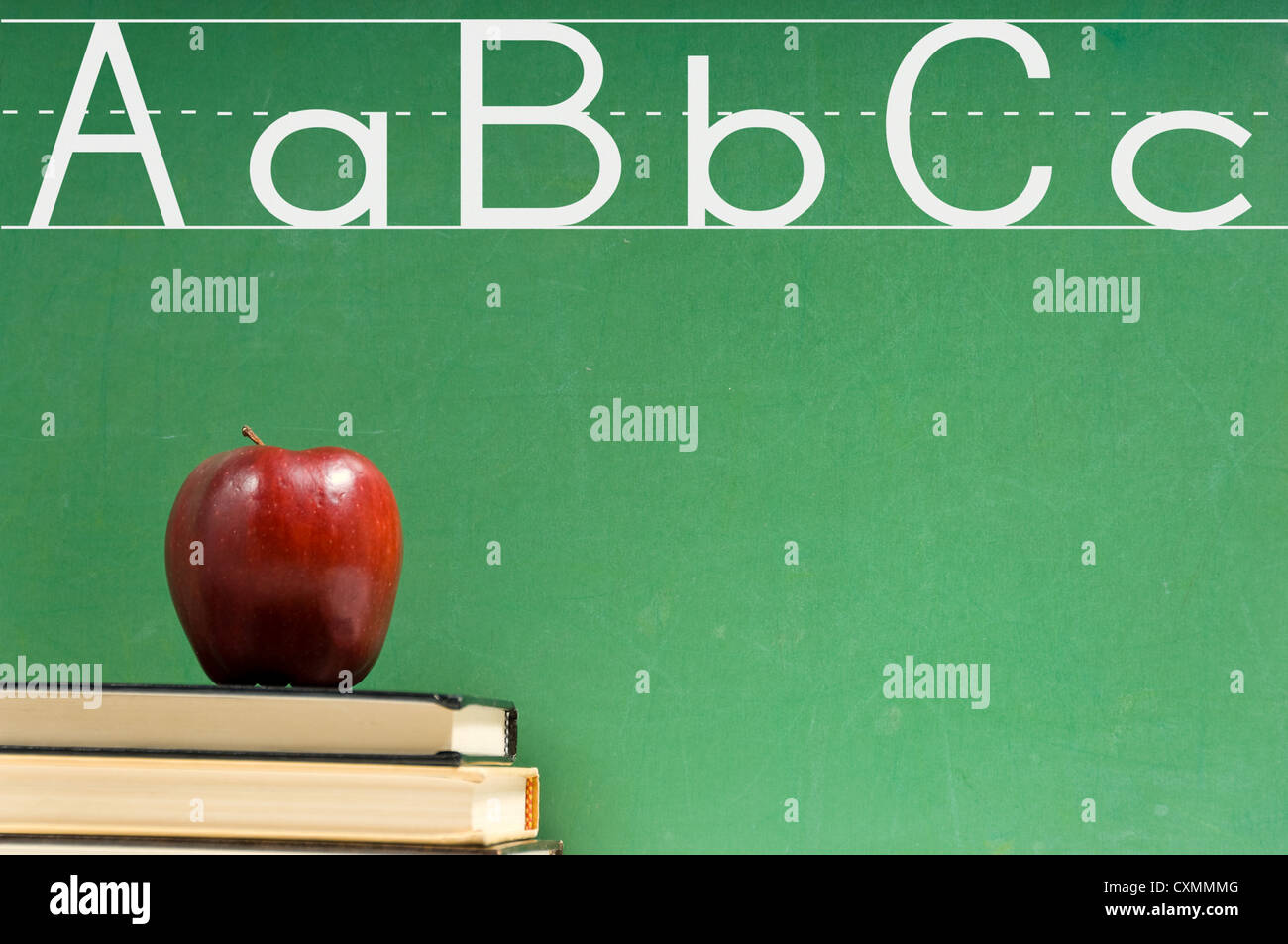 School books and apple in front of school chalkboard, with alphabet ...