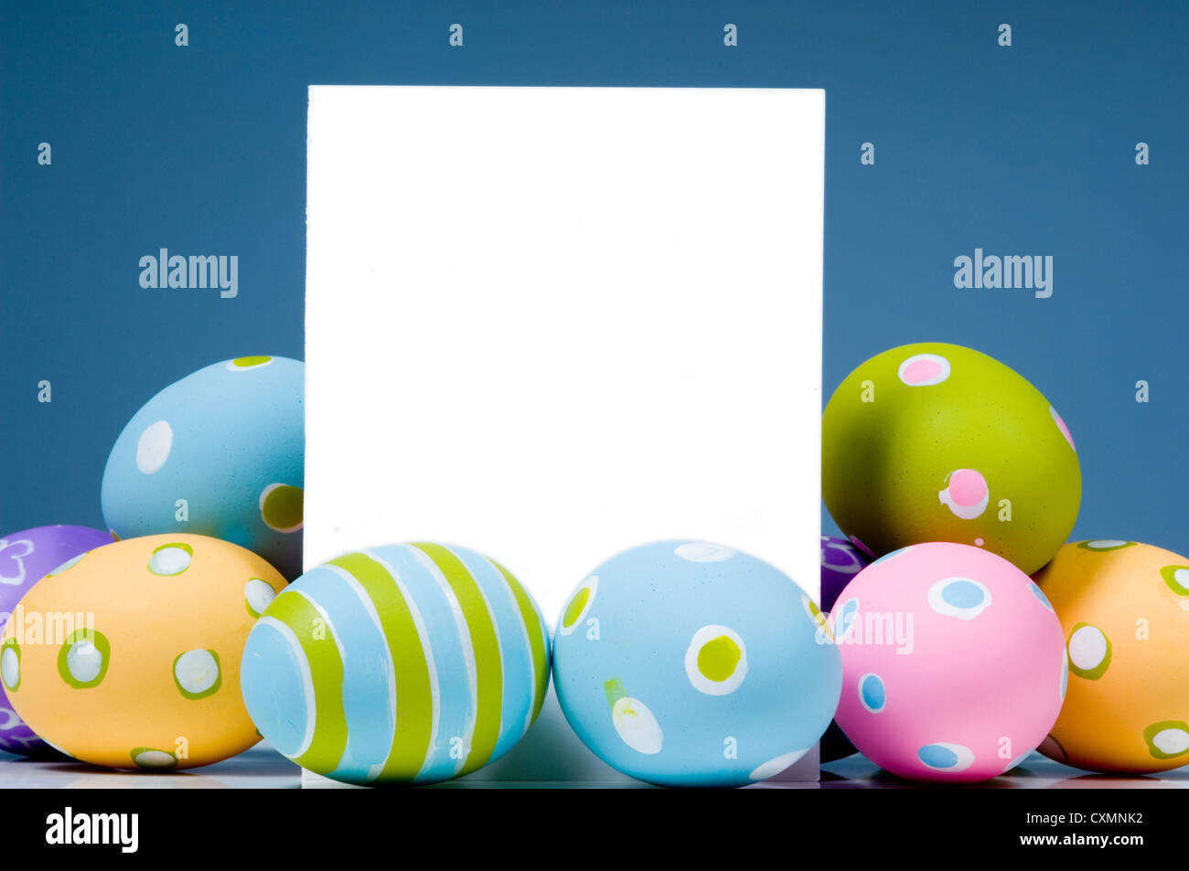Brightly colored Easter egg surrounding blank, white note card with ...