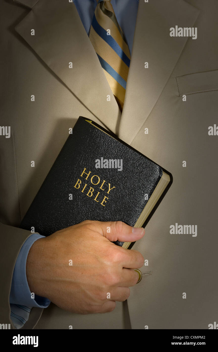 Man holding a Holy BIble dressed in a business suit with a necktie ...