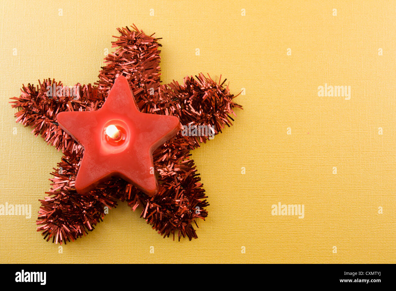 red Christmas star shaped candle on tinsel star with soft gold ...