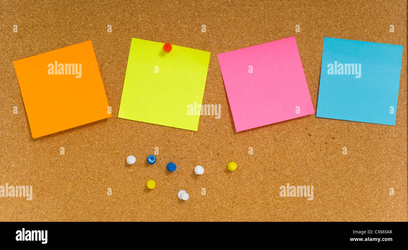 Blank sticky notes on a brown corkboard or bulletin board with colored ...