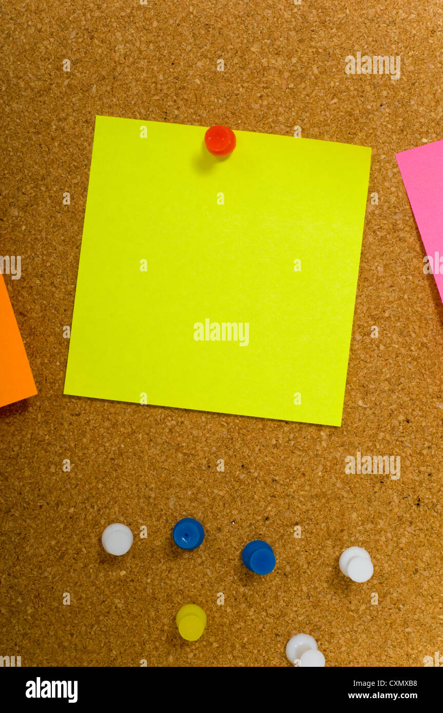Blank sticky notes on a brown corkboard or bulletin board with colored ...