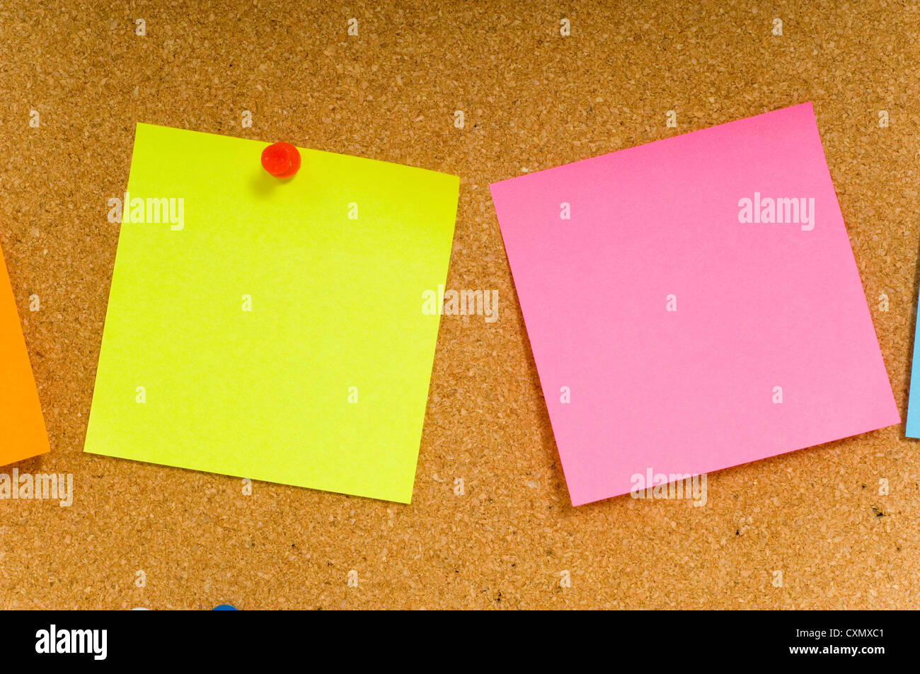 Blank sticky notes on a brown corkboard or bulletin board with colored ...