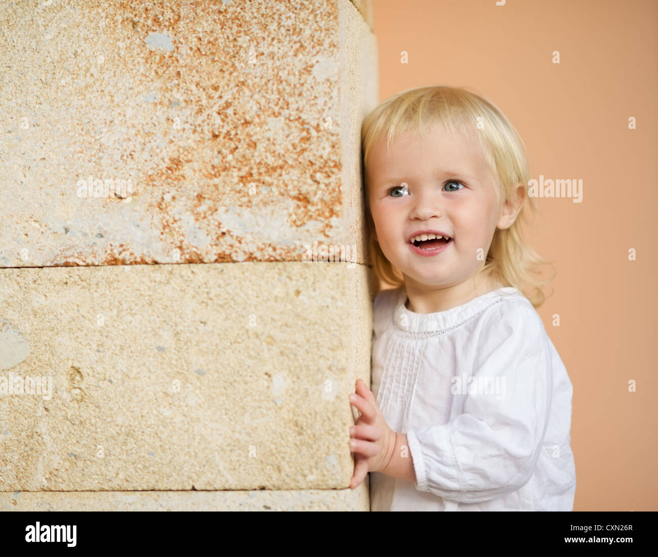 Portrait of baby leaning against wall Stock Photo - Alamy