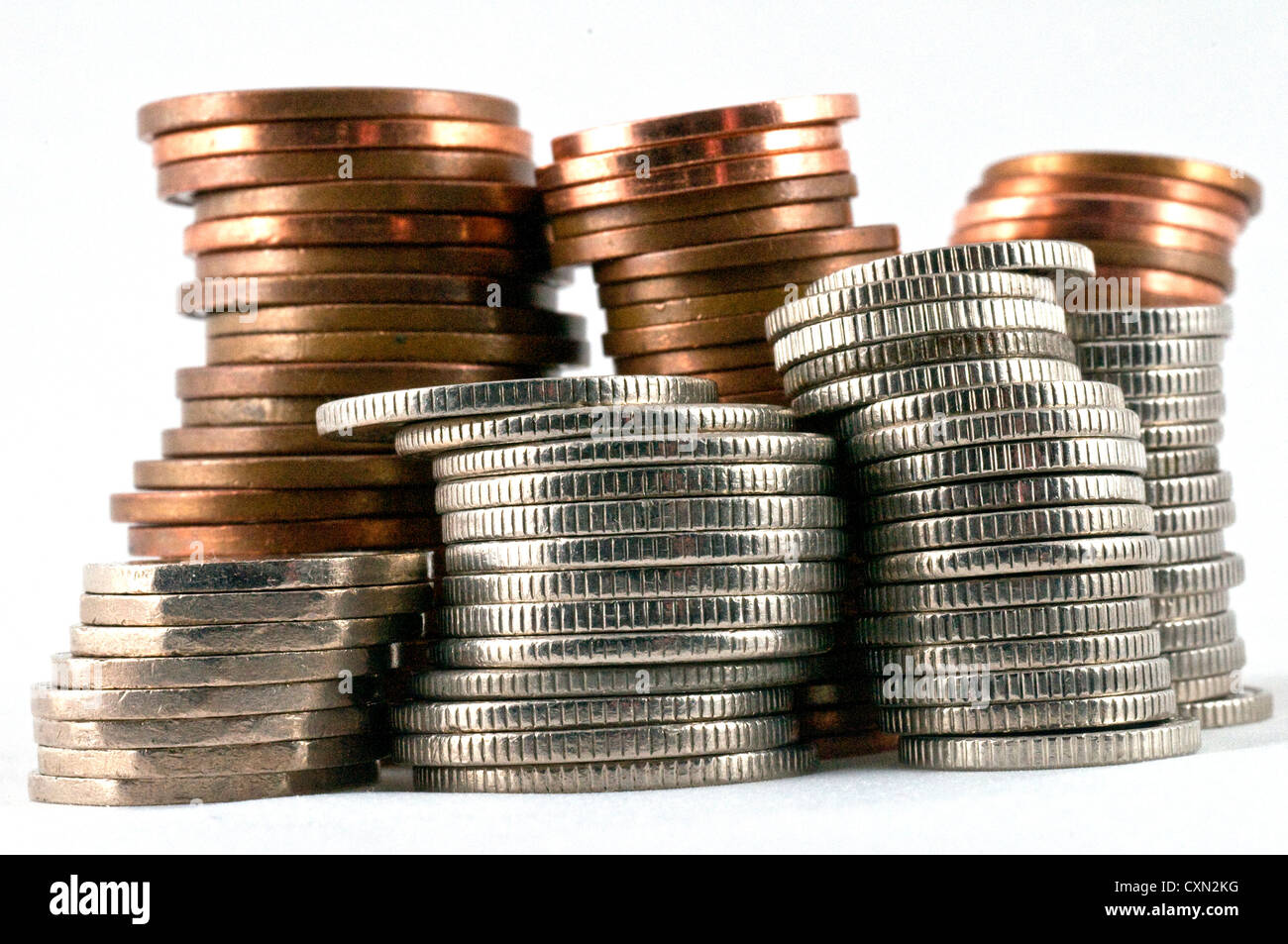 Stacks of silver & copper coins piled irregularly on a white background ...
