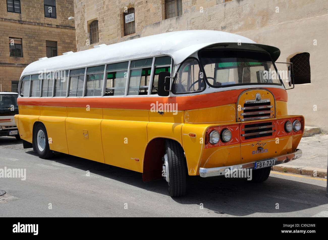 Yellow bus in street in Malta. 3/4 length shot from front in bright ...