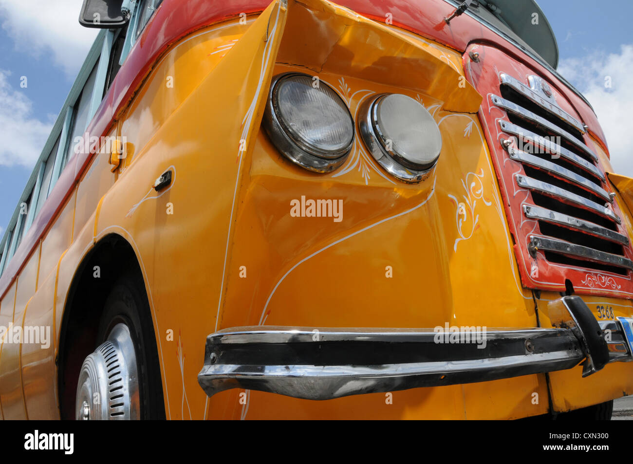 Low angle wide shot of bright yellow vintage bus in Malta. Blue sky all ...