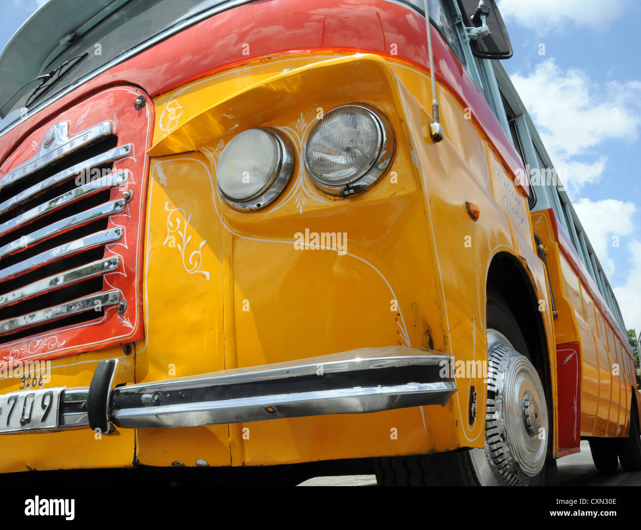Low angle close up of bright yellow bus in Malta. Clear blue sky ...