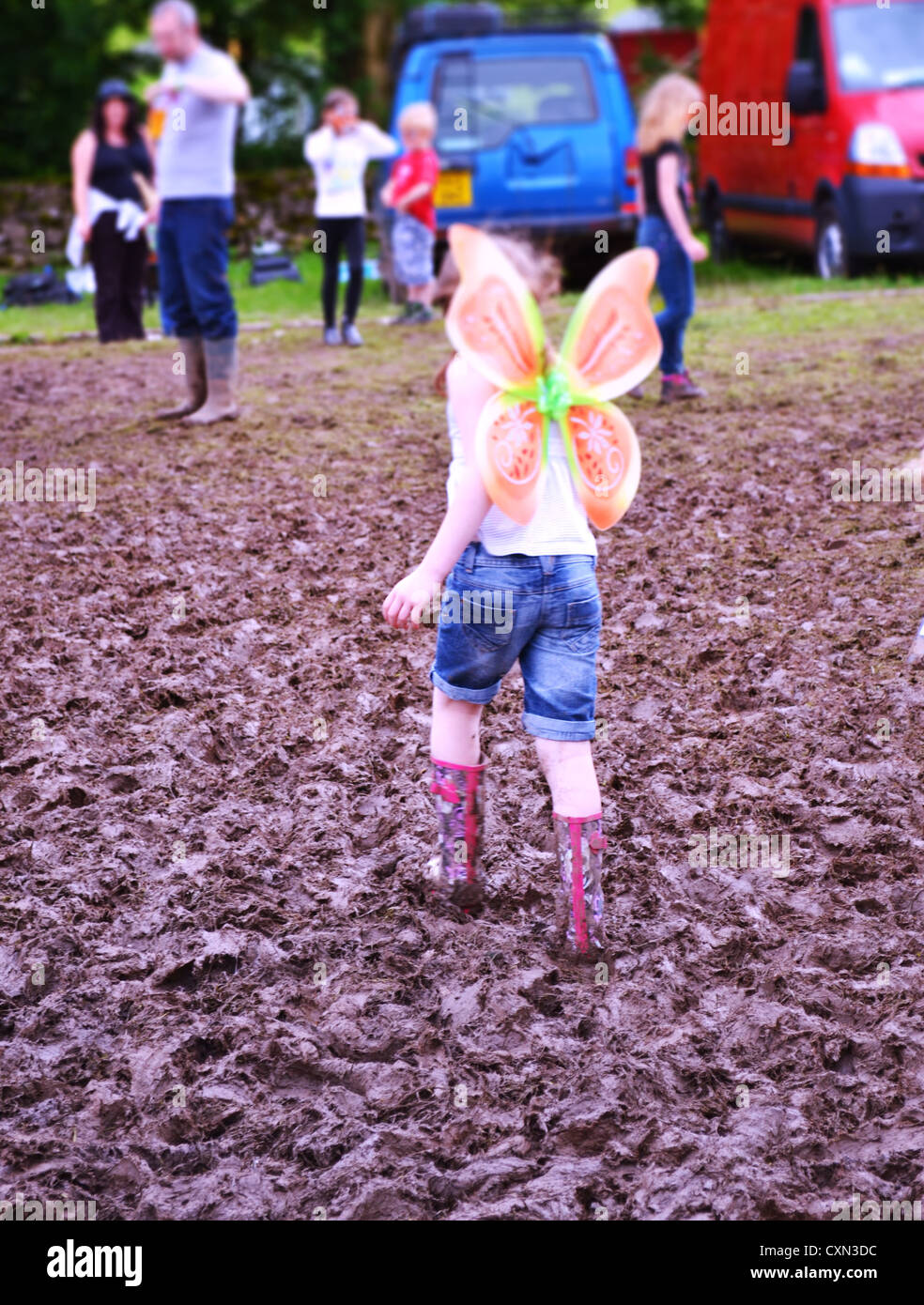 A young girl wearing angel wings wades through the mud of a British ...