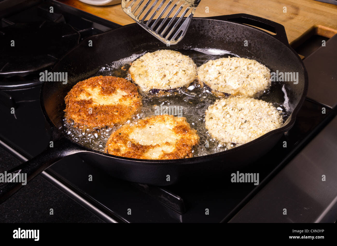 Frying slices of eggplant in cast iron skillet Stock Photo - Alamy