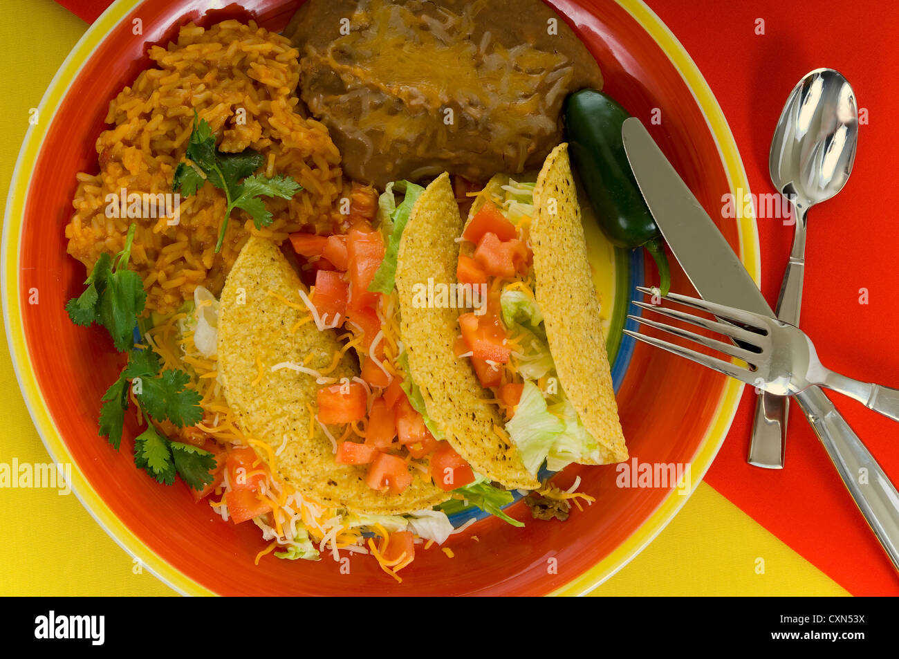 Mexican food plate with tacos, bean and rice on brightly colored plate ...