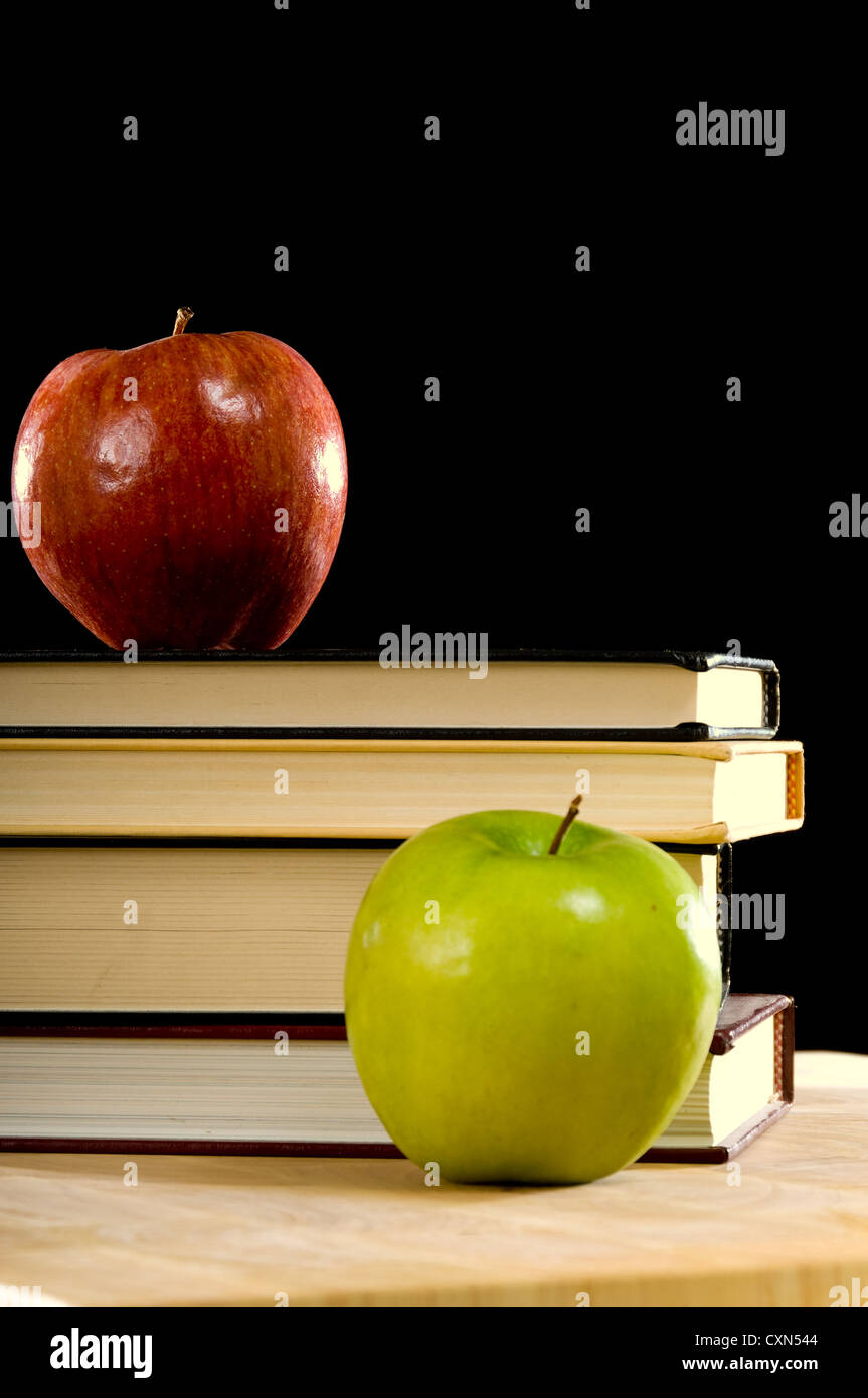 A red and green apple with school textbooks on black background Stock ...