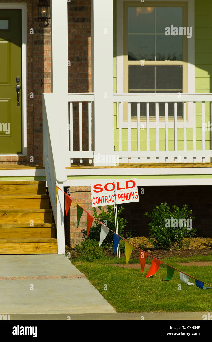 Sold sign in front of colorful house with flags etc Stock Photo - Alamy