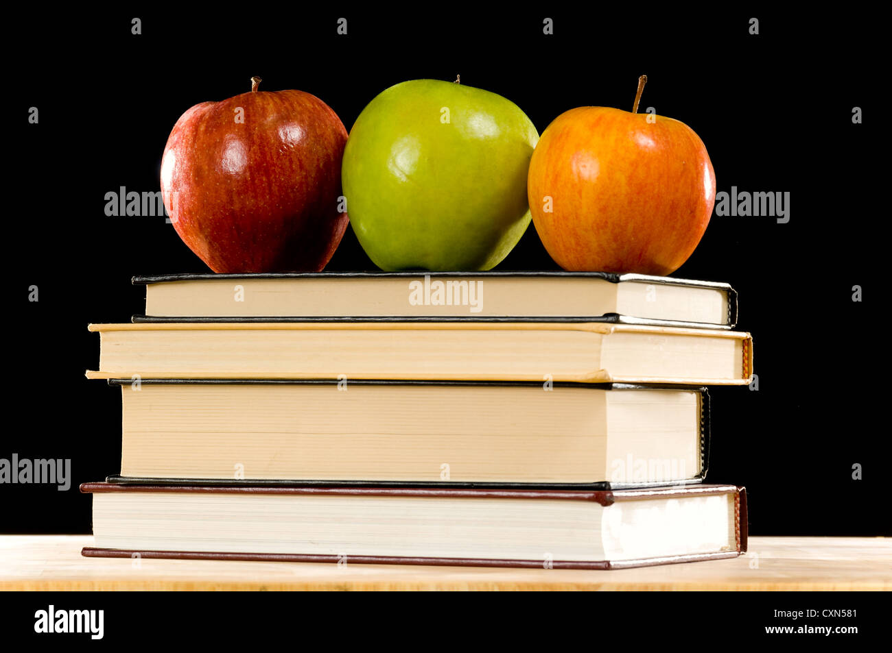 Variety of apples on top of a stack of school books Stock Photo - Alamy