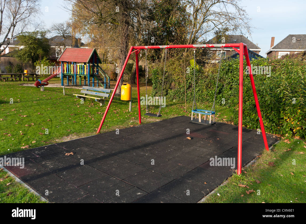 children's playground with a double red swing Stock Photo - Alamy