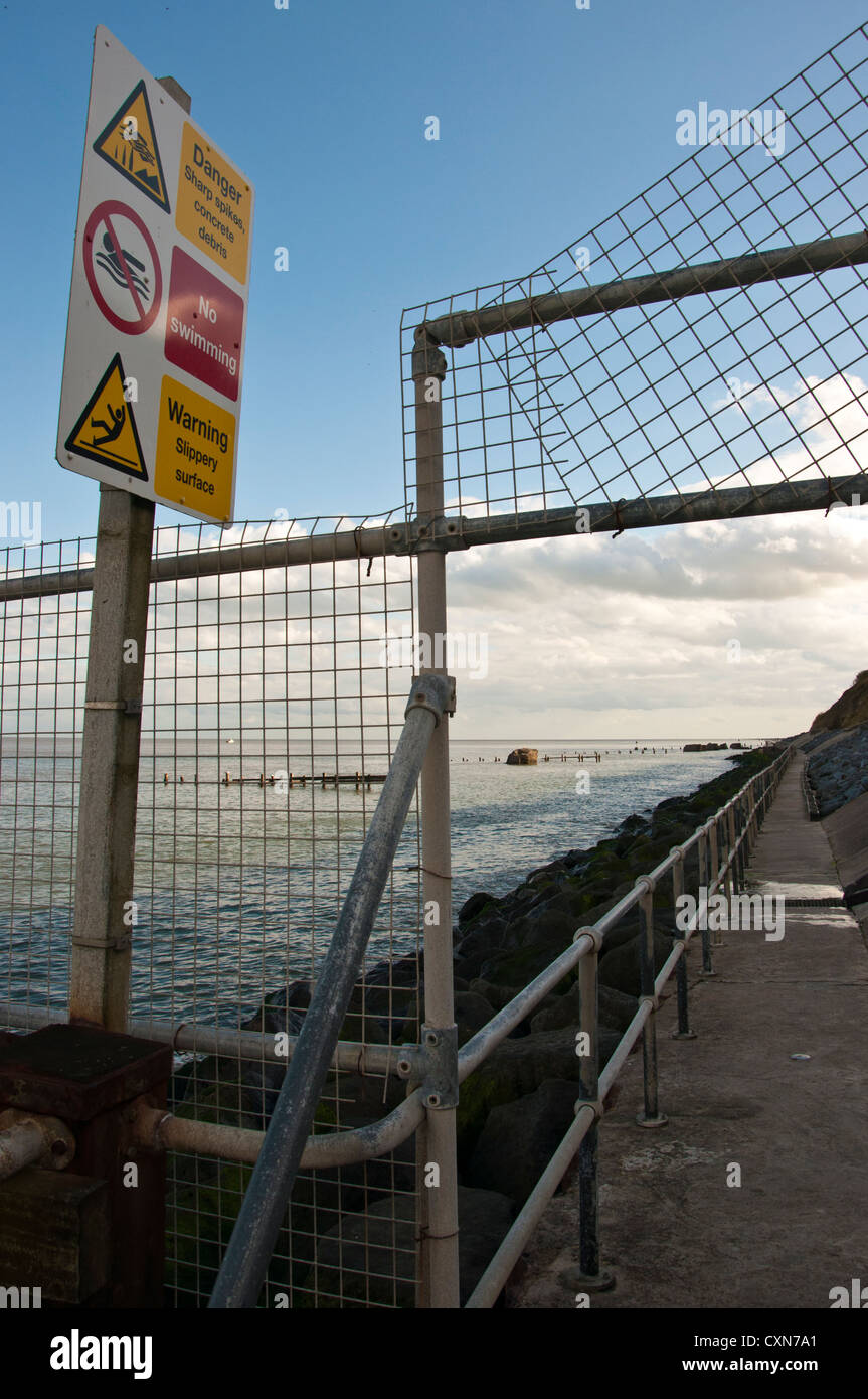 Fence and warning signs on sea wall path Corton Cliffs Stock Photo - Alamy