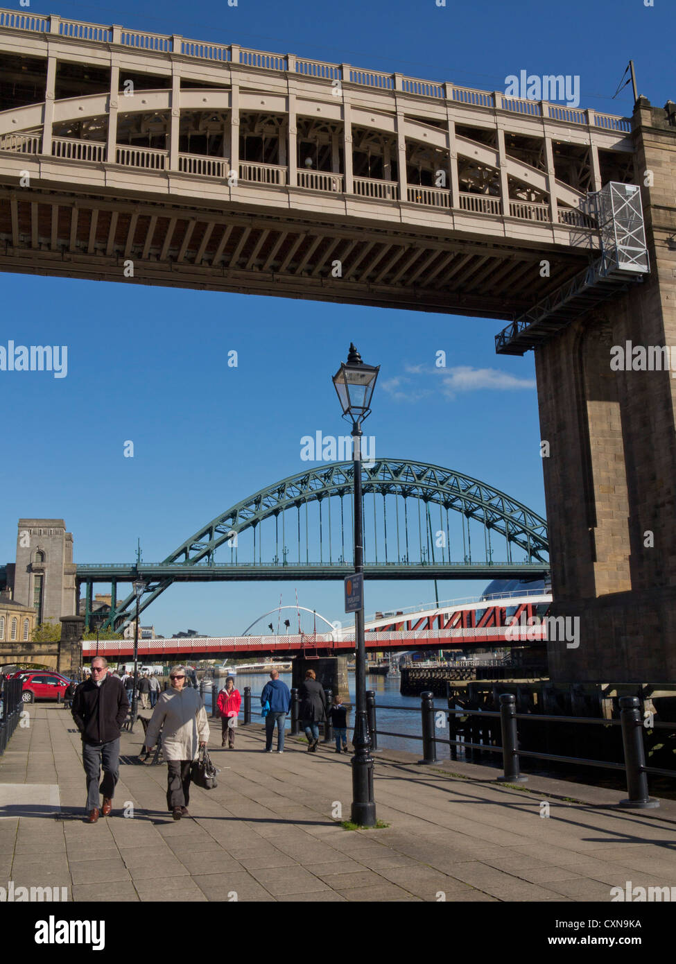 People walk and cycle on riverside by Tyne bridges in Newcastle ...