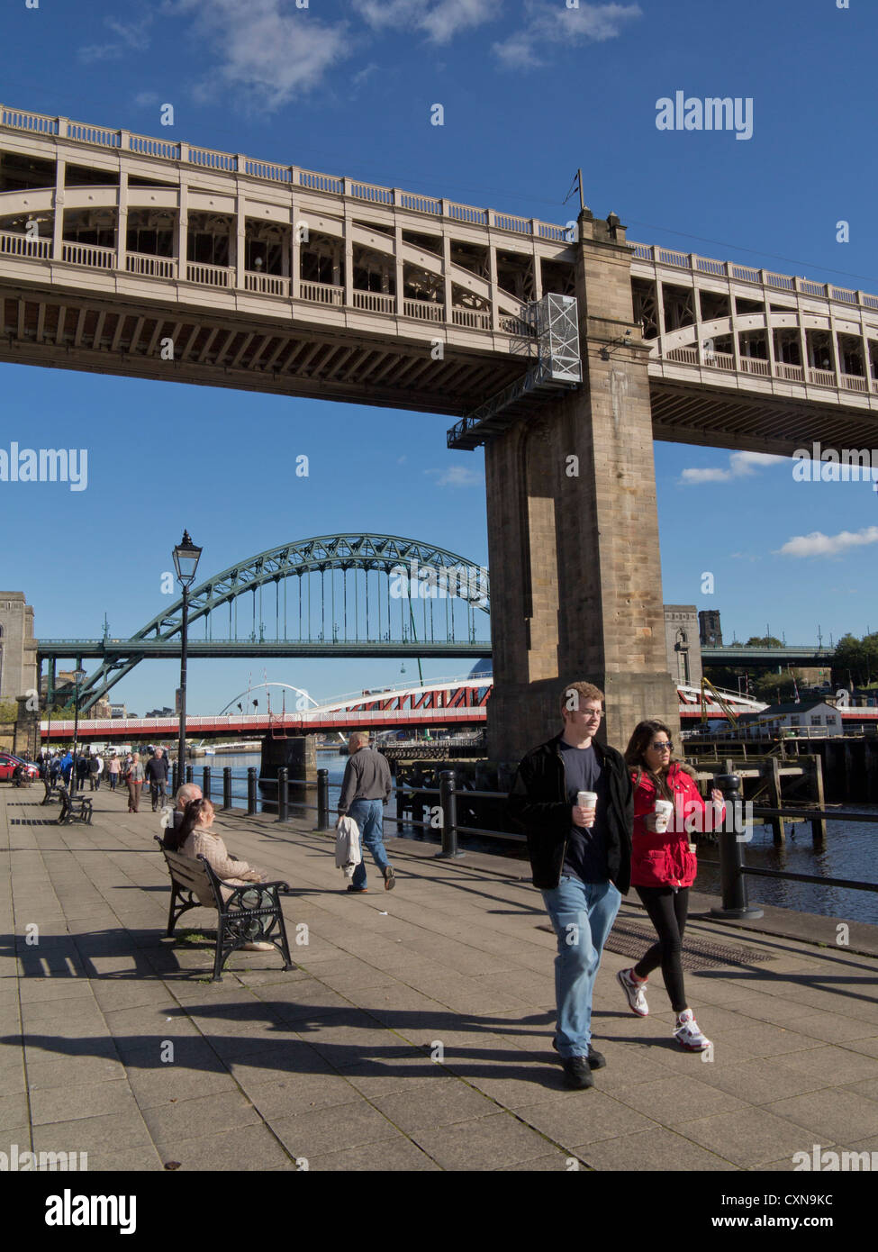 People walk and cycle on riverside by Tyne bridges in Newcastle ...