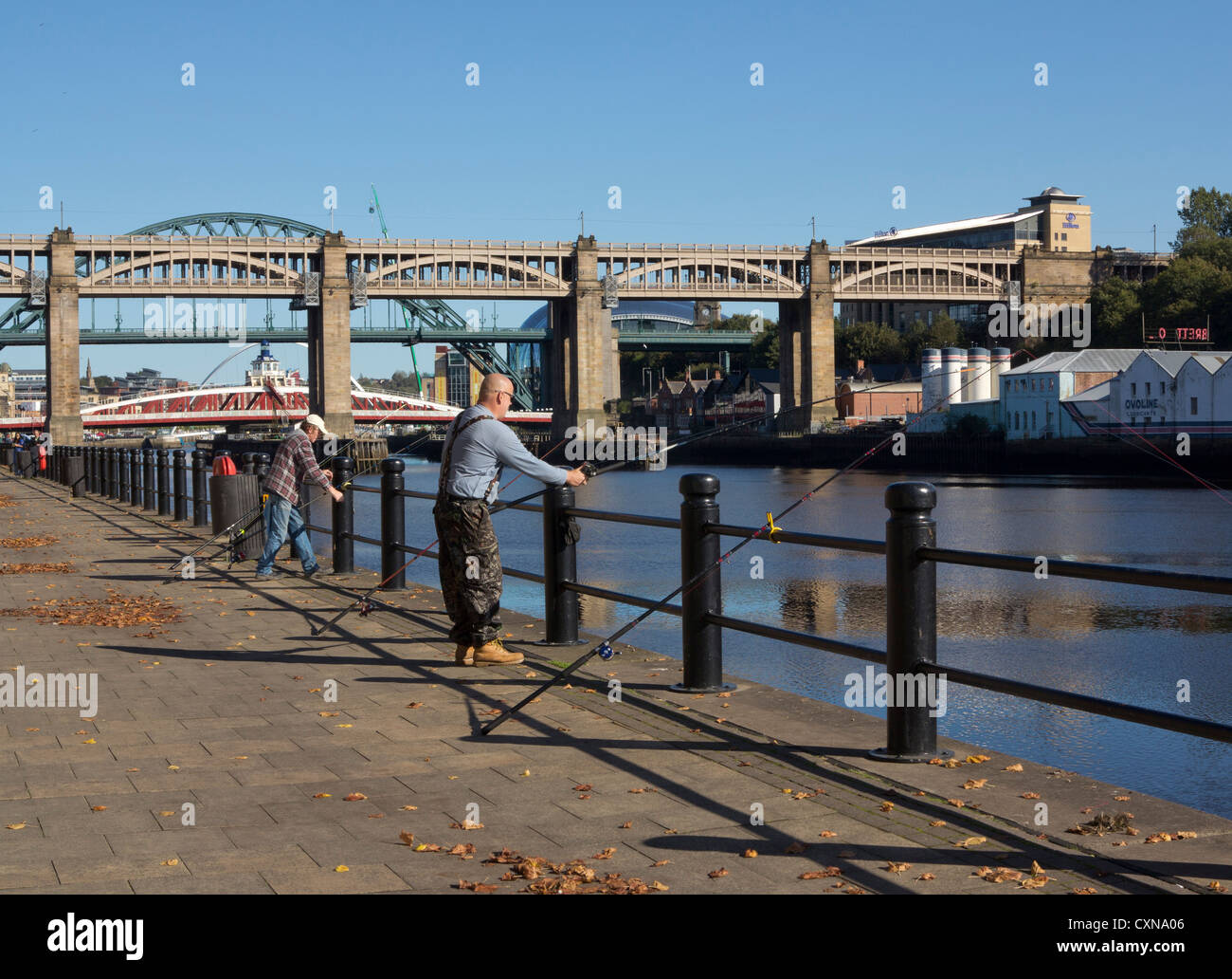 People fish on riverside by Tyne bridges in Newcastle, England, UK ...