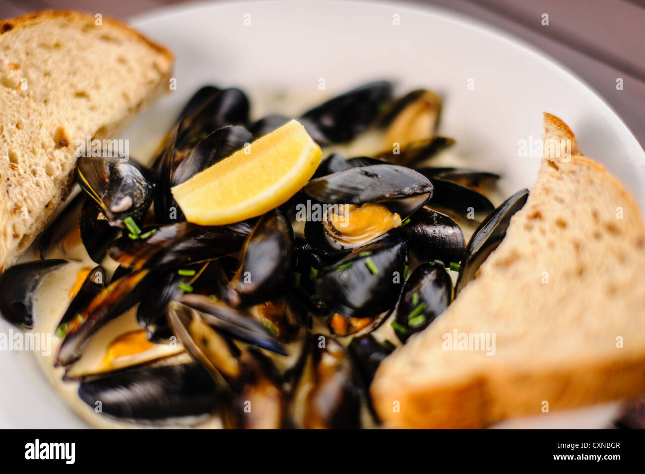 A bowl of fresh Cornish mussels, served with fresh granary bread and a ...