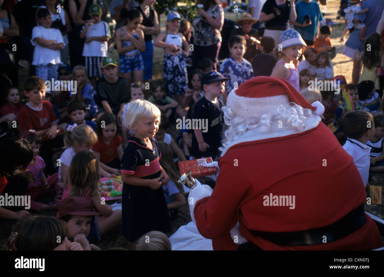 Father Christmas handing out presents to children Stock Photo - Alamy