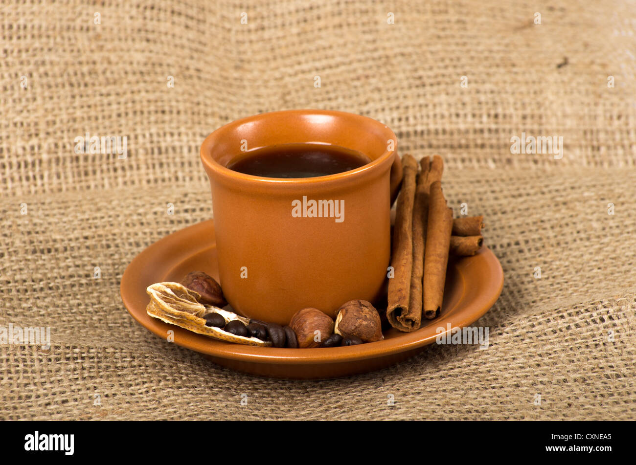 Coffee cup with cinnamon, coffe beans, nuts and lemon over sacking ...