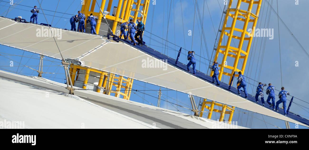 Up At The O2, people kitted out in blue overalls & walking on roof of ...