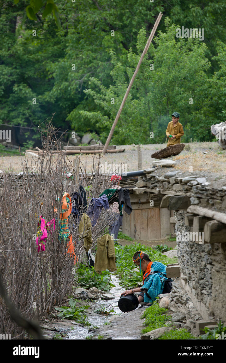 Kalash woman washing a bowl in the stream, Kalasha Grum, Rumbur Valley ...