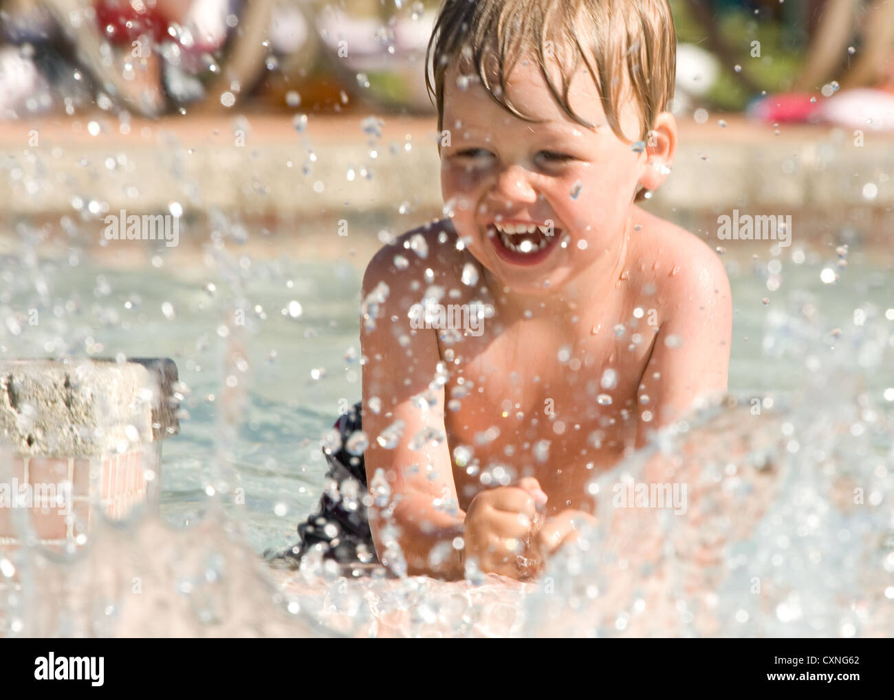 Young child plashing in the swimming pool in summer time Stock Photo ...