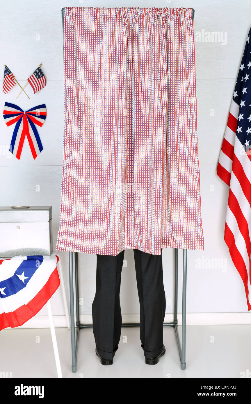A man standing inside a voting booth at his local polling place ...