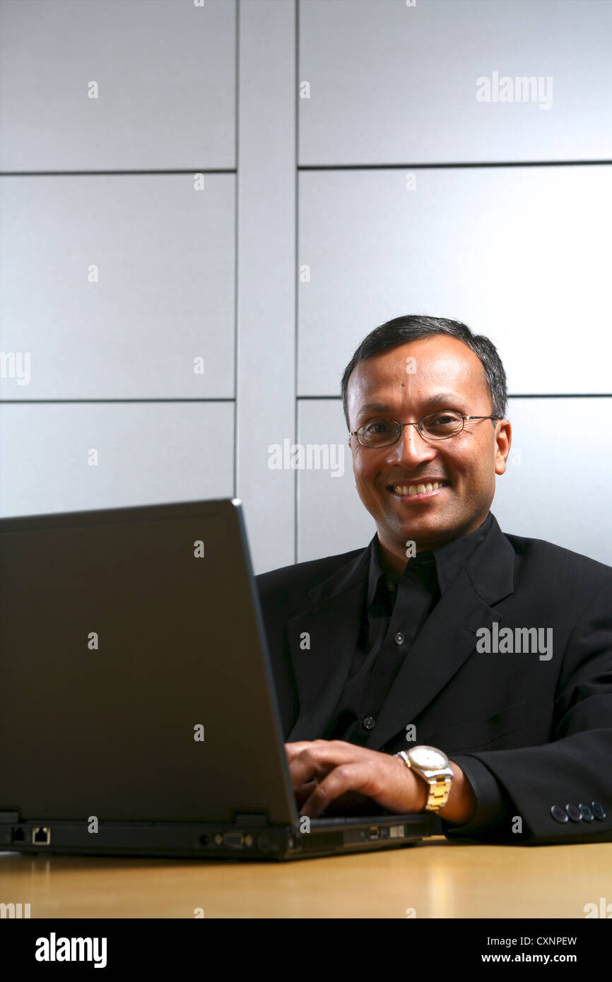 Professional sat at desk working with laptop Stock Photo - Alamy