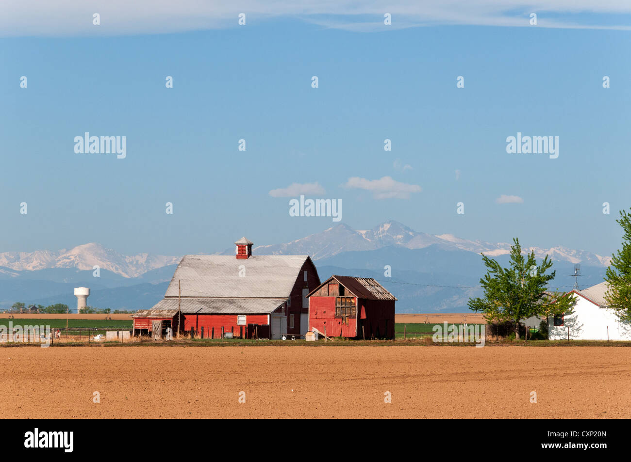 Old red barn between plowed field and the Rocky Mountains in the far ...
