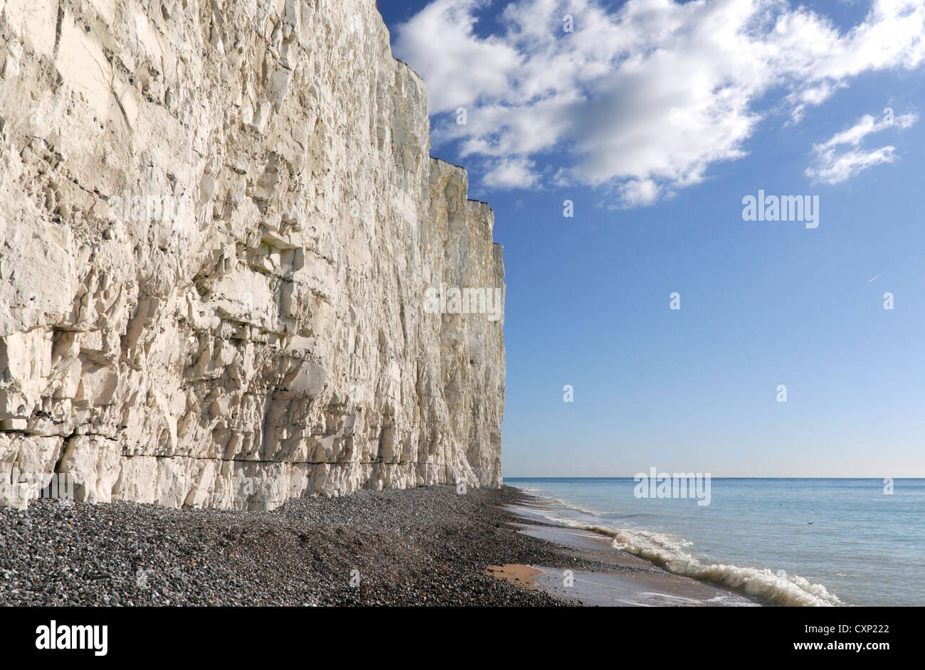Seen from a shingle coastline below white chalk cliffs, sea nad blue ...