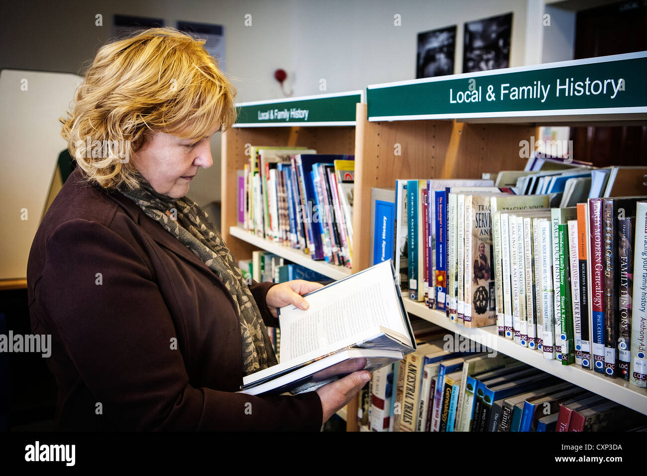 Lady reading a book from the Local & Family History section of a ...