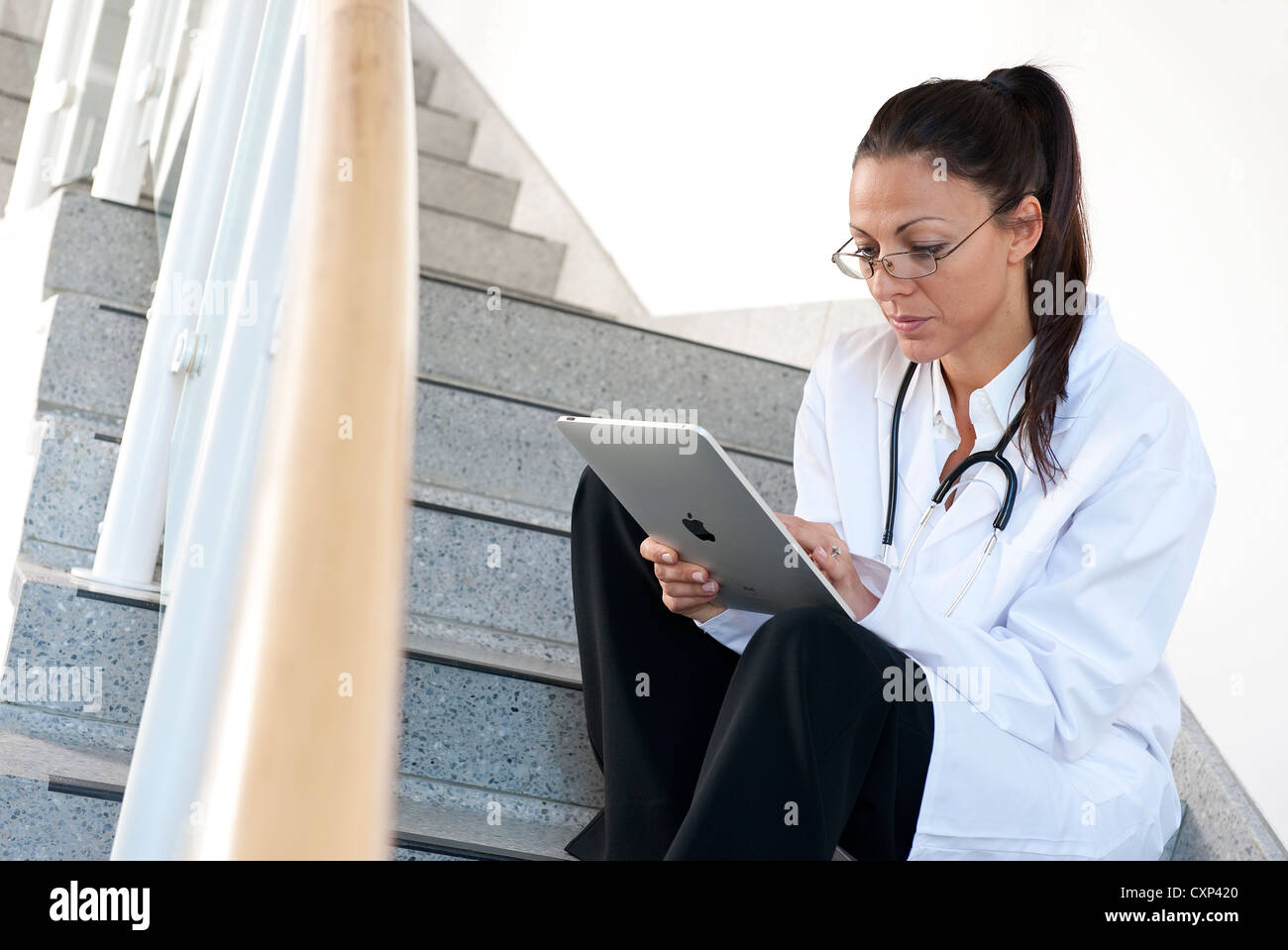 female doctor sitting on stairs using ipad tablet computer Stock Photo ...