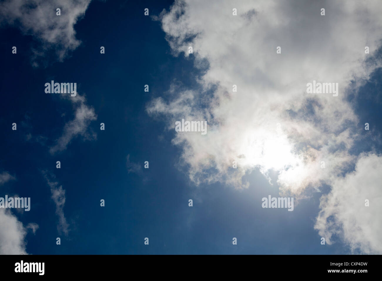 Sun behind light wispy cloud with blue sky Stock Photo - Alamy