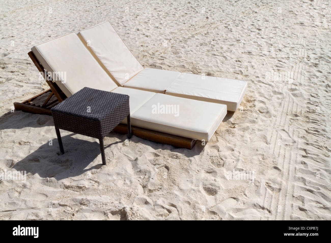 A pair of beach lounge chairs with table Stock Photo - Alamy