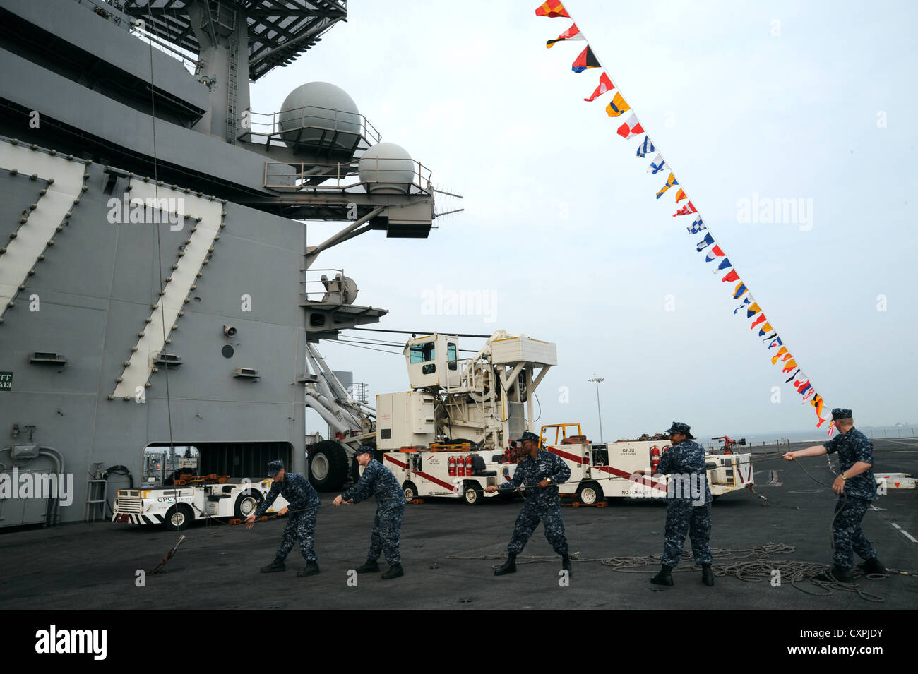 Sailors aboard the USS George H.W. Bush raise flags and pennants on the ...